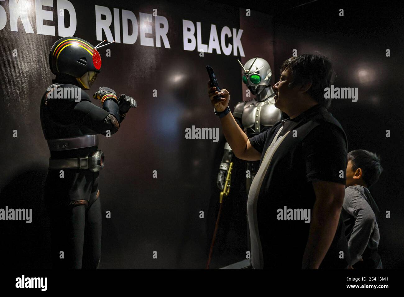 A fan of the Kamen Rider drama series takes a photo with the Kamen ...