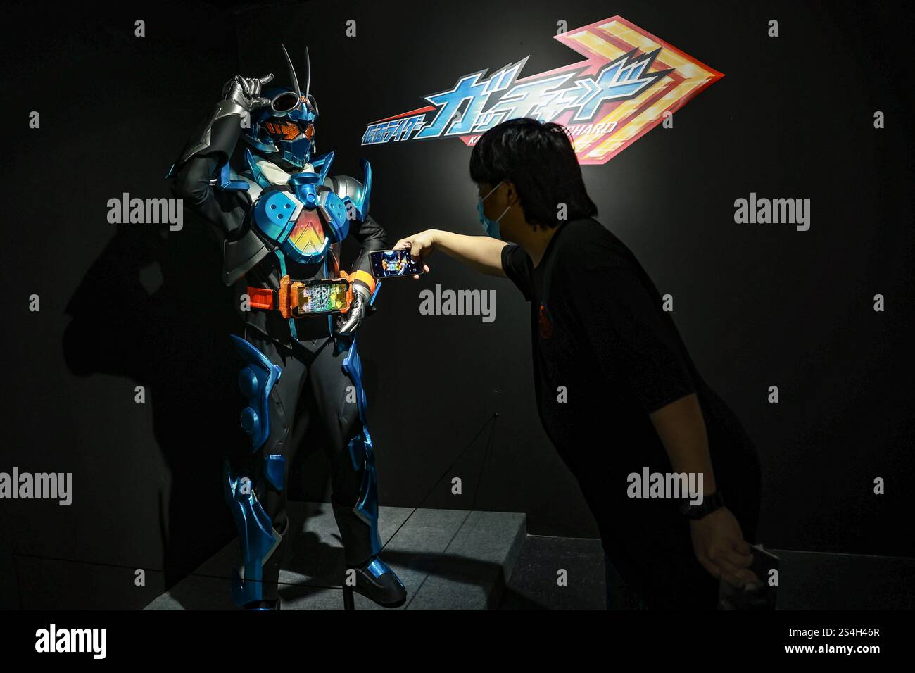 A fan of the Kamen Rider drama series takes a photo with the Kamen ...