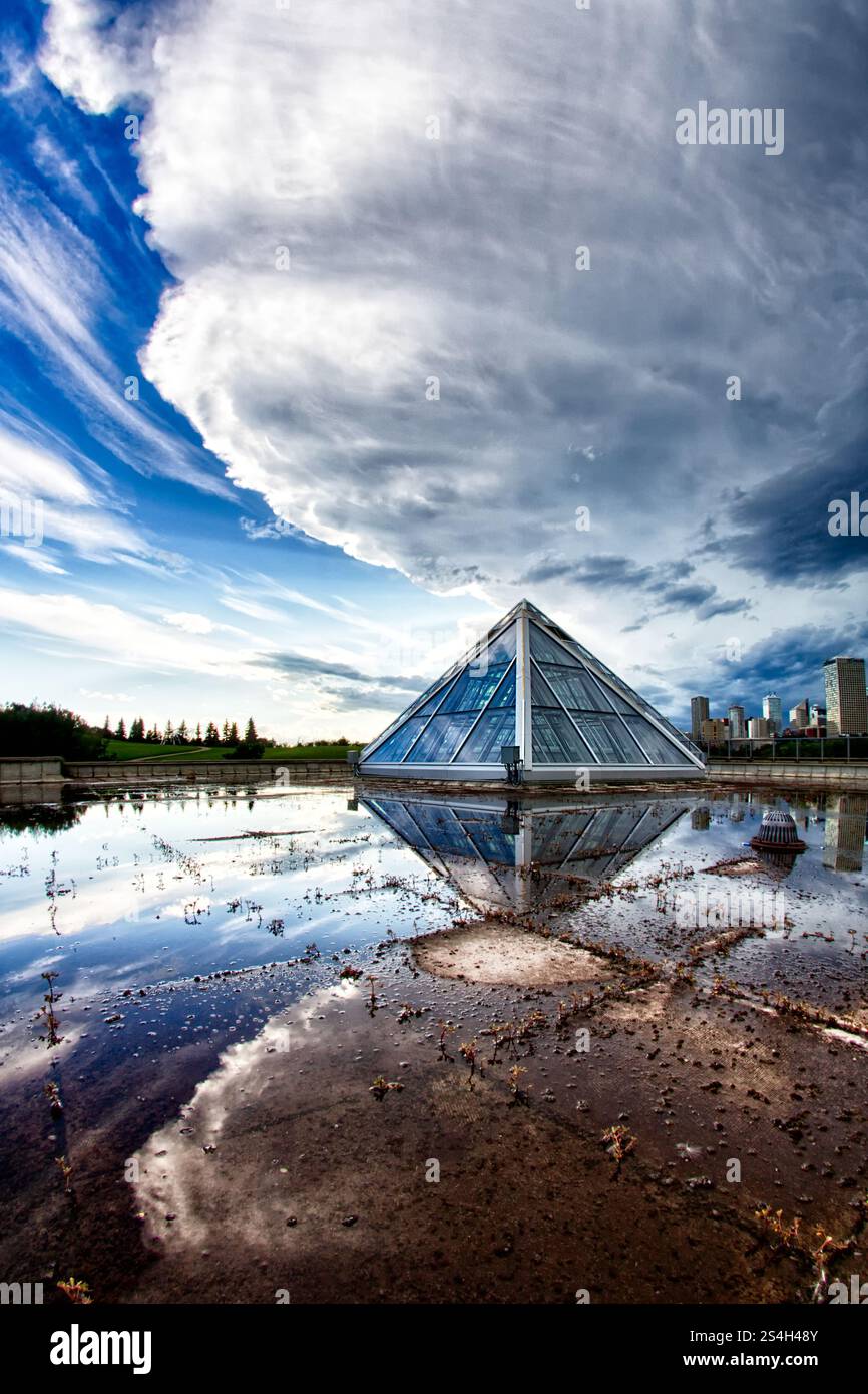 A pyramid-shaped building is reflected in the water. The sky is cloudy ...