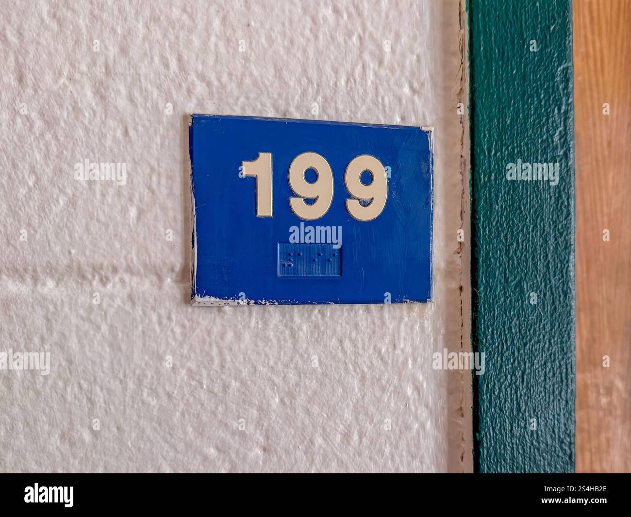 Blue 199 sign with white lettering and braille, on a blue block wall ...