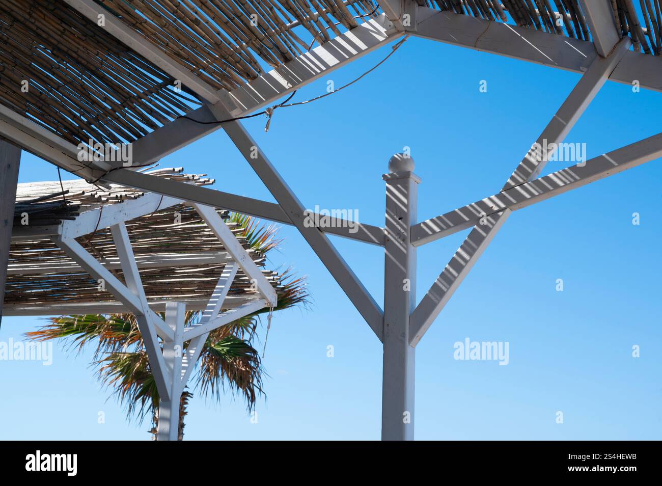 Beach bar thatched roof with palm tree shade and blue sky sun on the ...