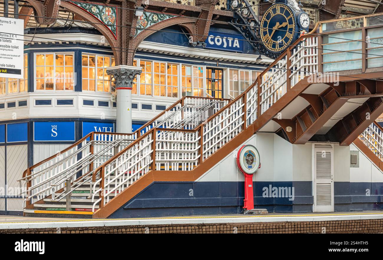 A railway station staircase leads up to a footbridge and an ornate ...