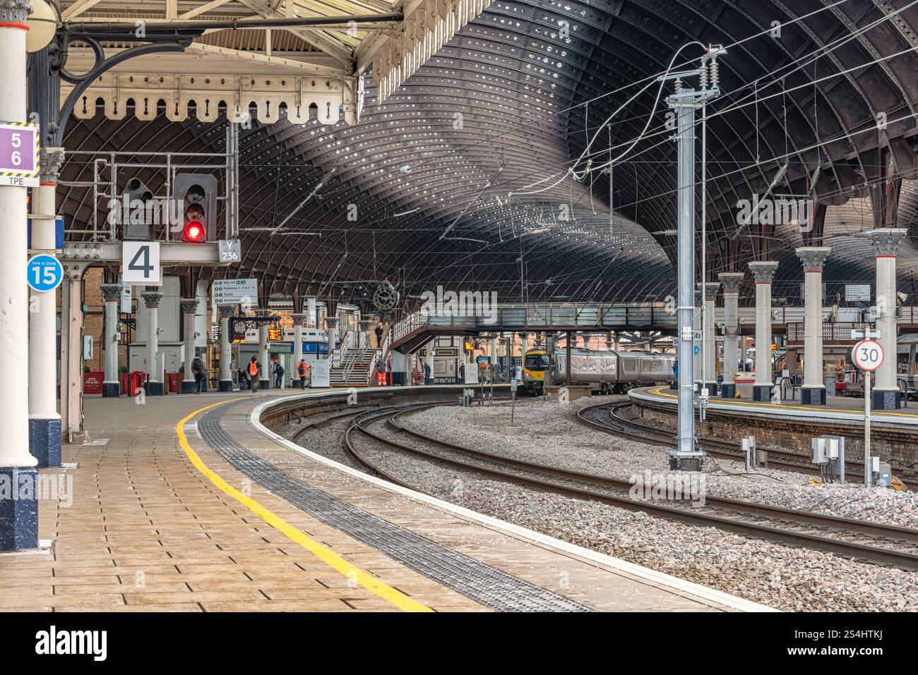 A railway station platform, lined by columns, curves, into a main concourse. A historic 19th ...