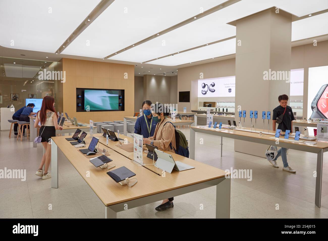 Asian woman looks at a selection of latest laptops in the Huawei Store ...