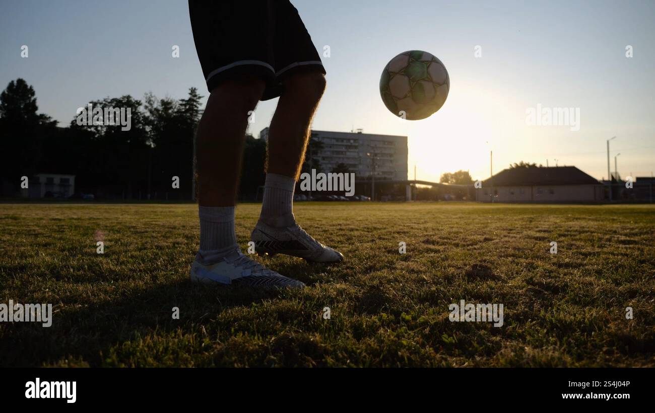 Legs of young man kicking ball at green field. Male feet of ...