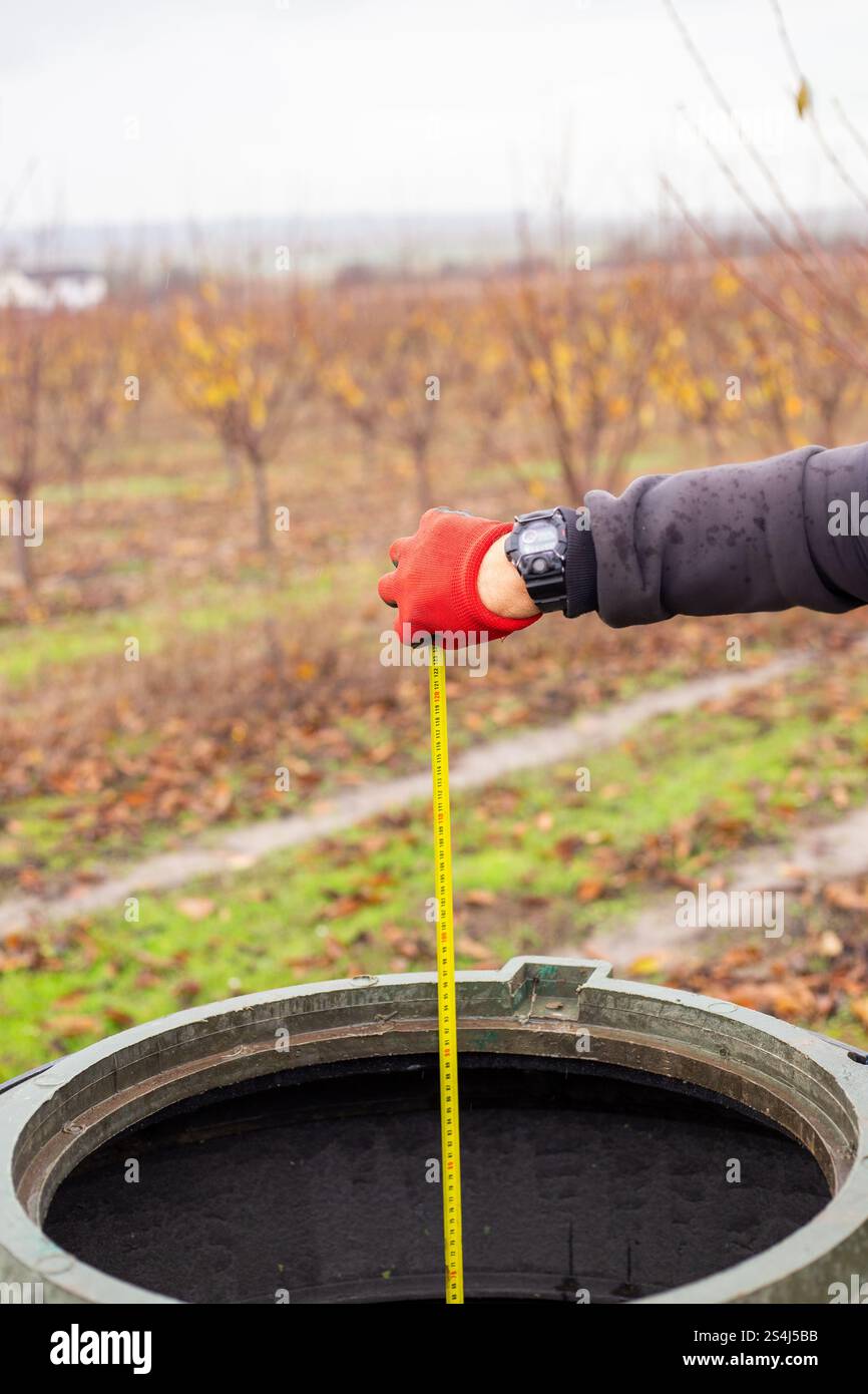 Worker installs water intake unit in well, measuring well depth ...