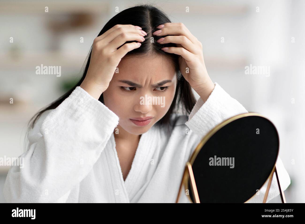 Angry asian lady checking her grey hair Stock Photo - Alamy