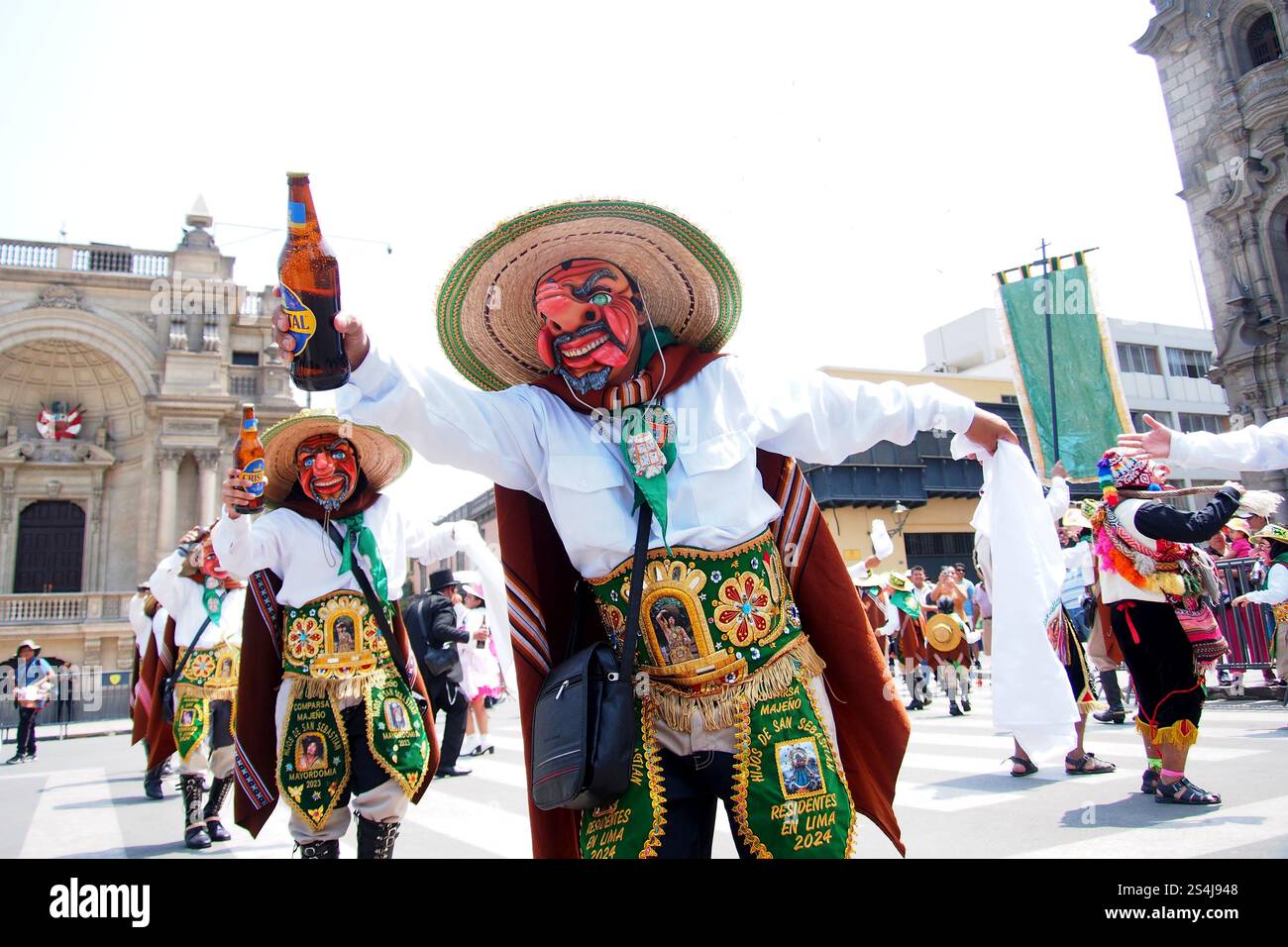 Masked dancers, with a bottle of beer, dancing in front of the ...