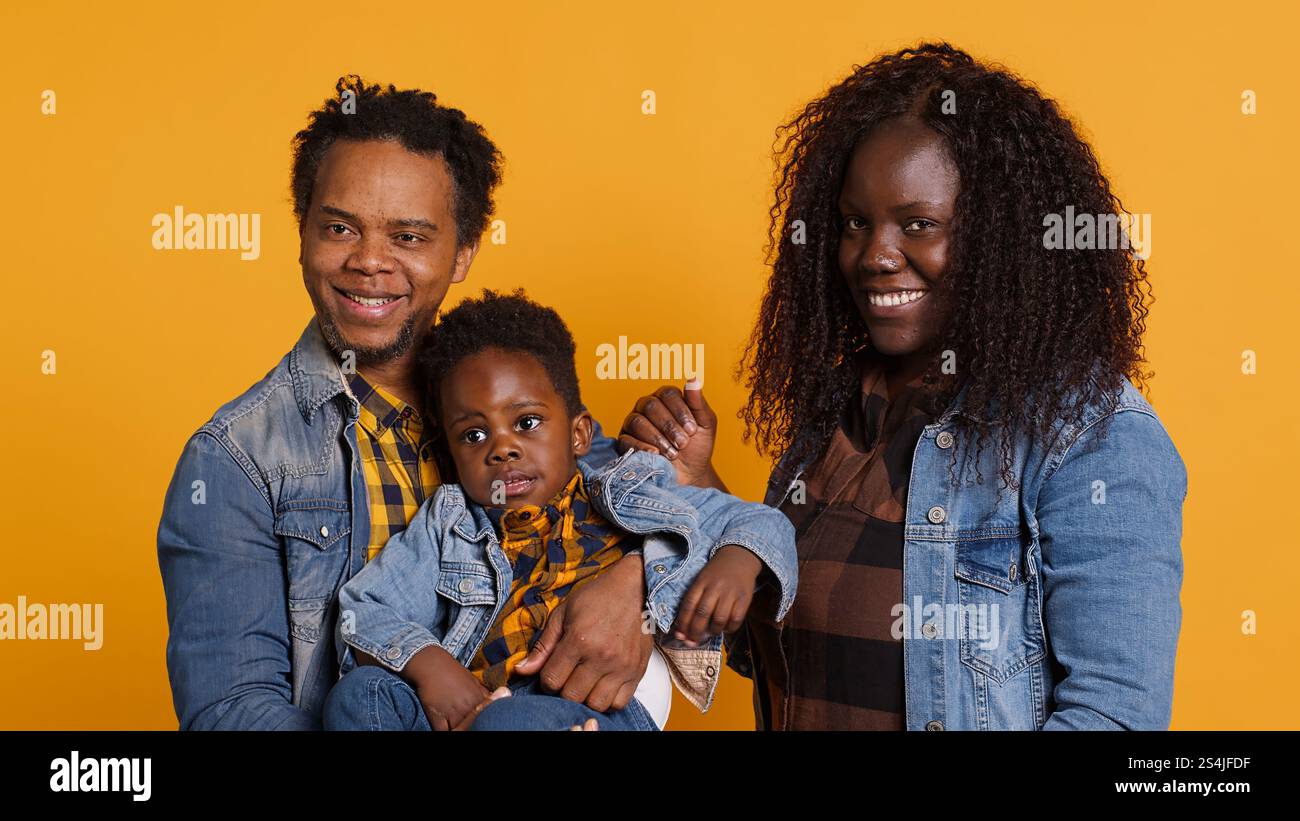 African american family smiling against yellow background in studio ...