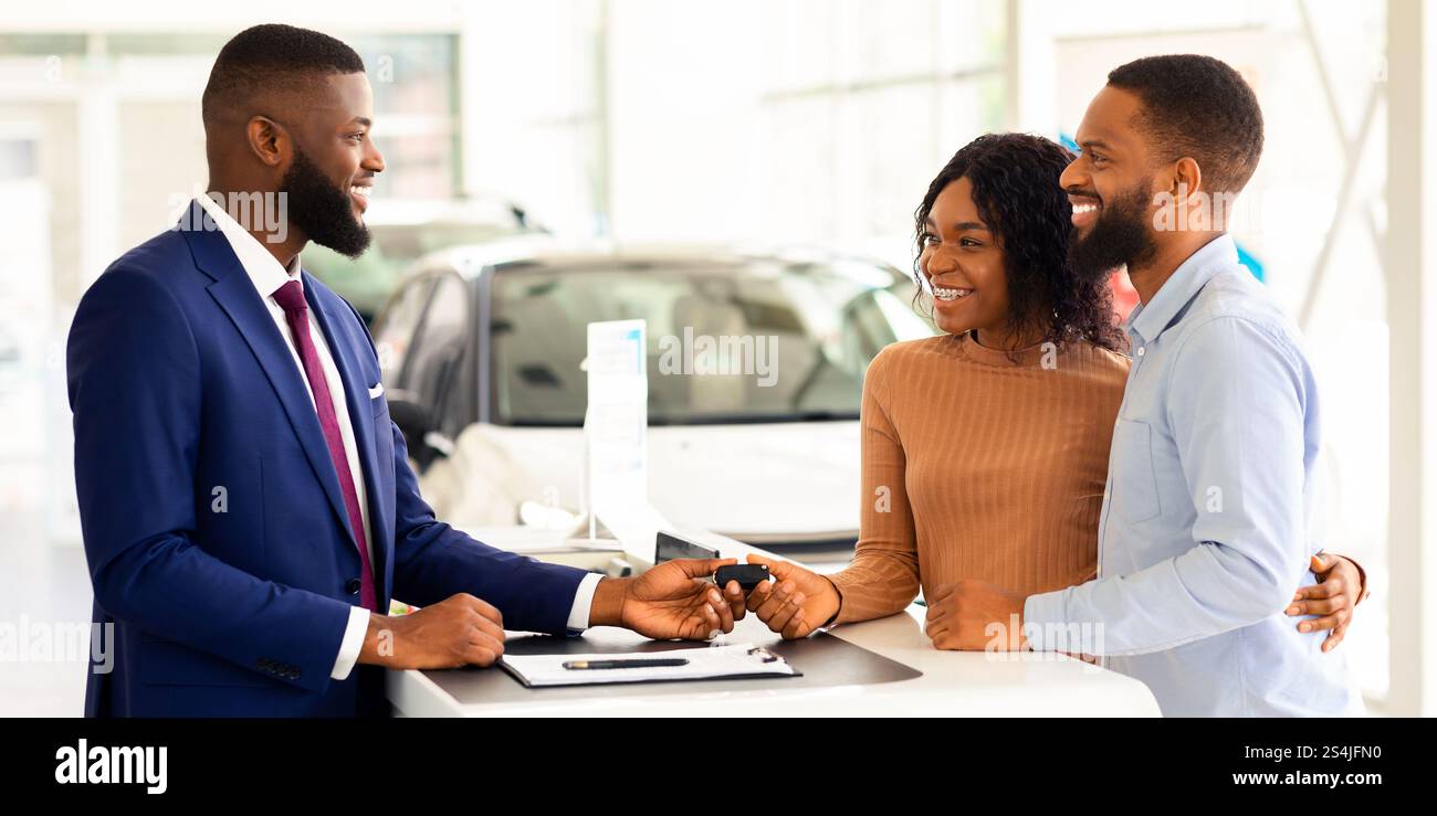 Purchasing Car. Happy Black Couple Key From Manager In Dealership ...