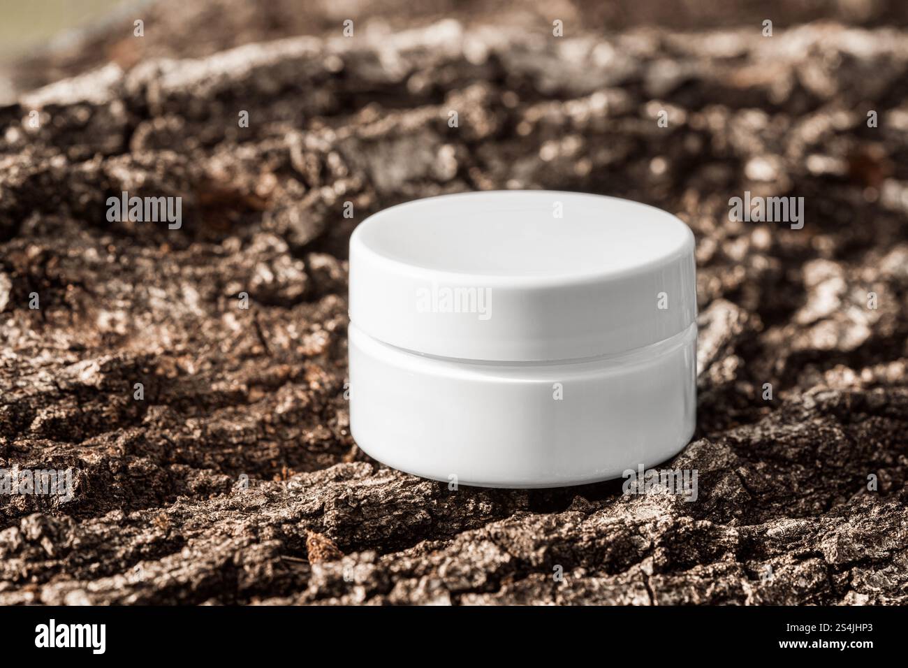 White cosmetic jar of firming cream on rugged tree bark surface display ...