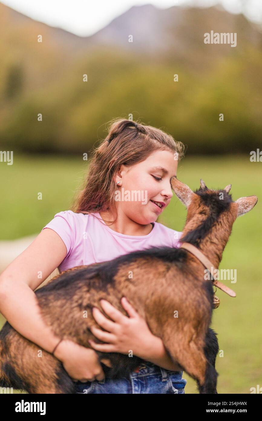 Young girl embracing a goat in an animal sanctuary during environmental ...