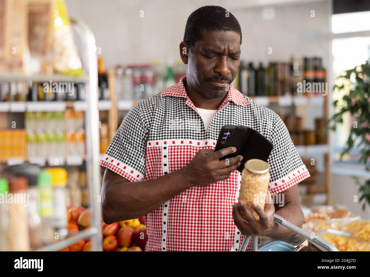 African man customer at shop scans QR code on canned beans jar using ...