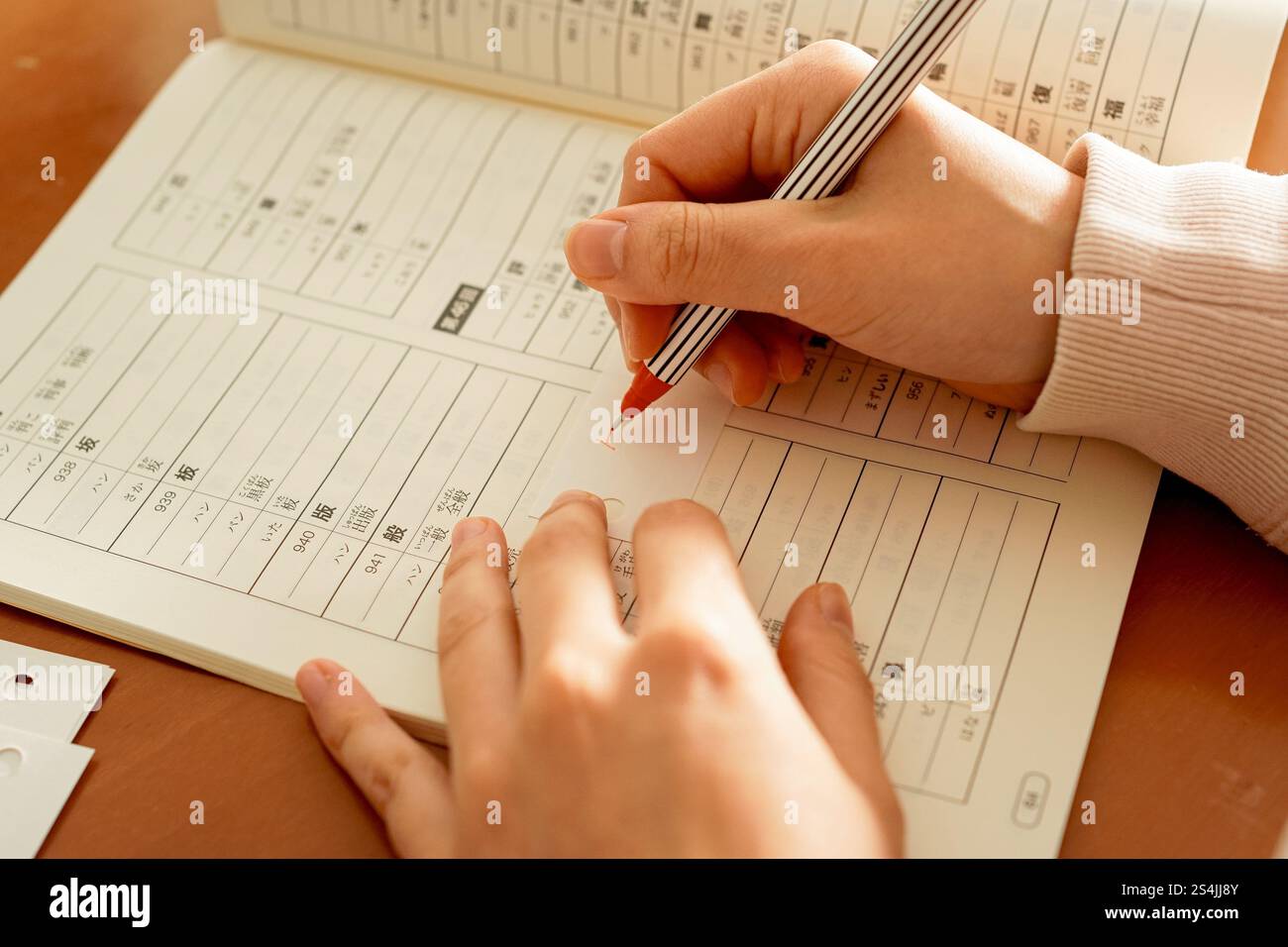 Close-up of a young foreign woman's hands as she is writing kanji to ...