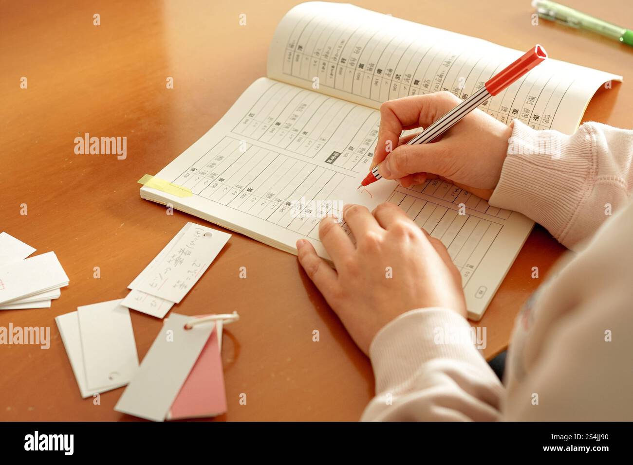 Close-up of a young foreign woman's hands as she is writing kanji to ...