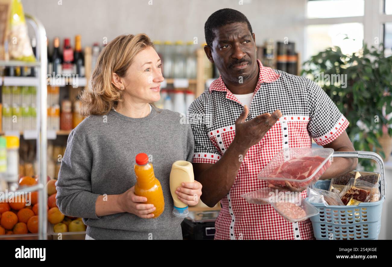 African husband and his wife are shopping in grocery store, looking for ...