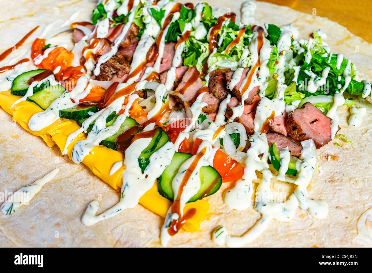 A colorful wrap features layers of grilled meat, fresh lettuce ...