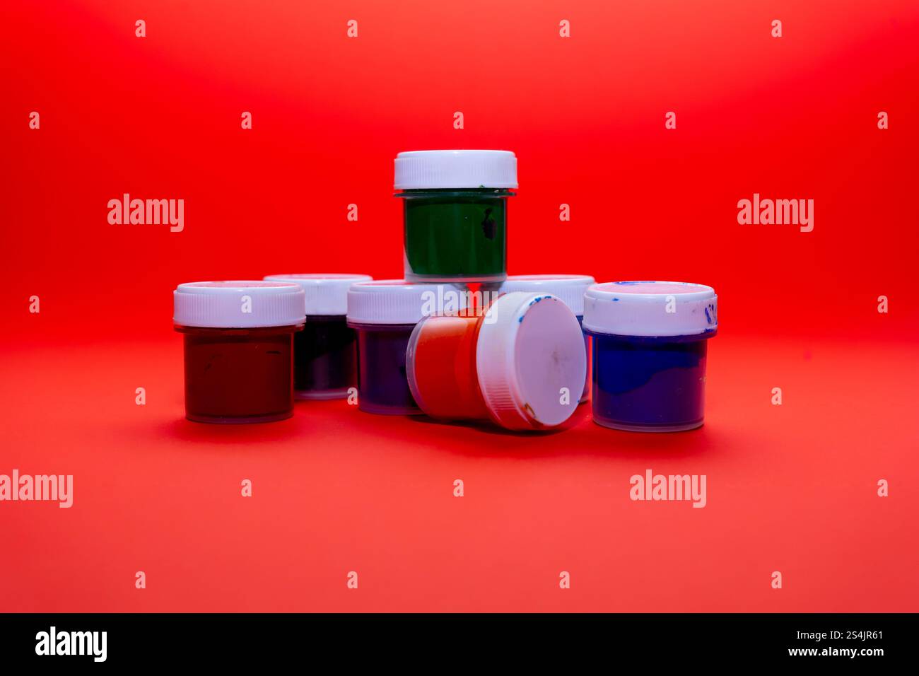 Several jars of paint in various colors are stacked against a striking ...