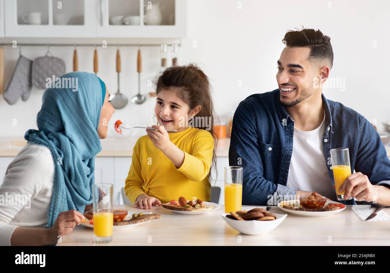 Little Arab Girl Feeding Mom While Having Breakfast With Parents In ...