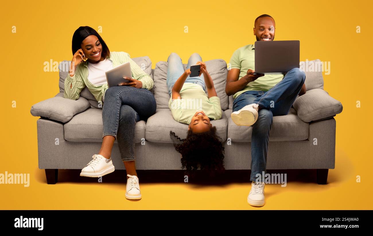 Gadgets addiction. Young black family of three using different ...