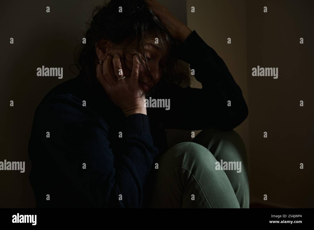 A person sitting contemplatively in dim lighting, expressing feelings ...