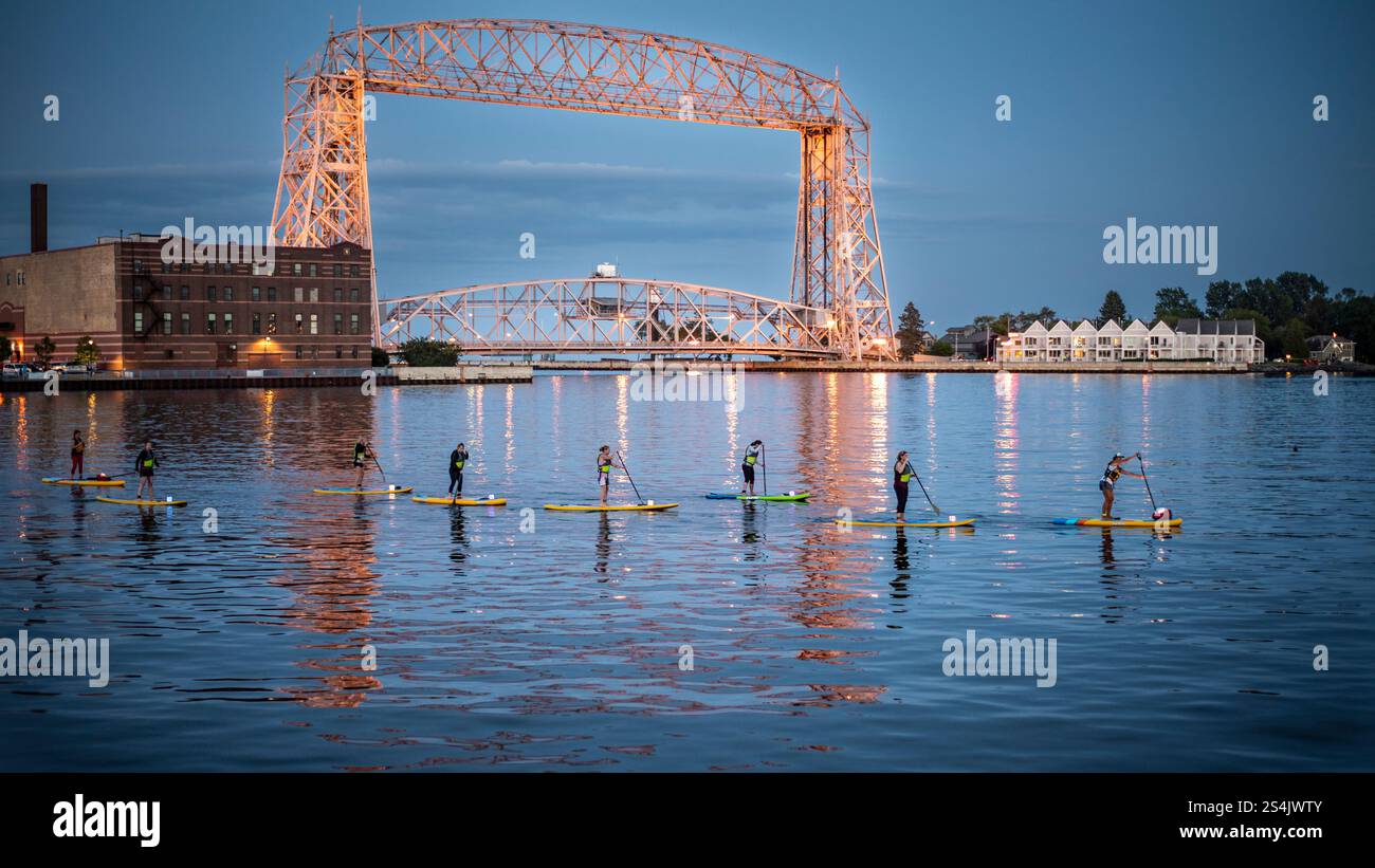 Group Paddle boarding at Twilight Near an Illuminated Iron Bridge Stock ...