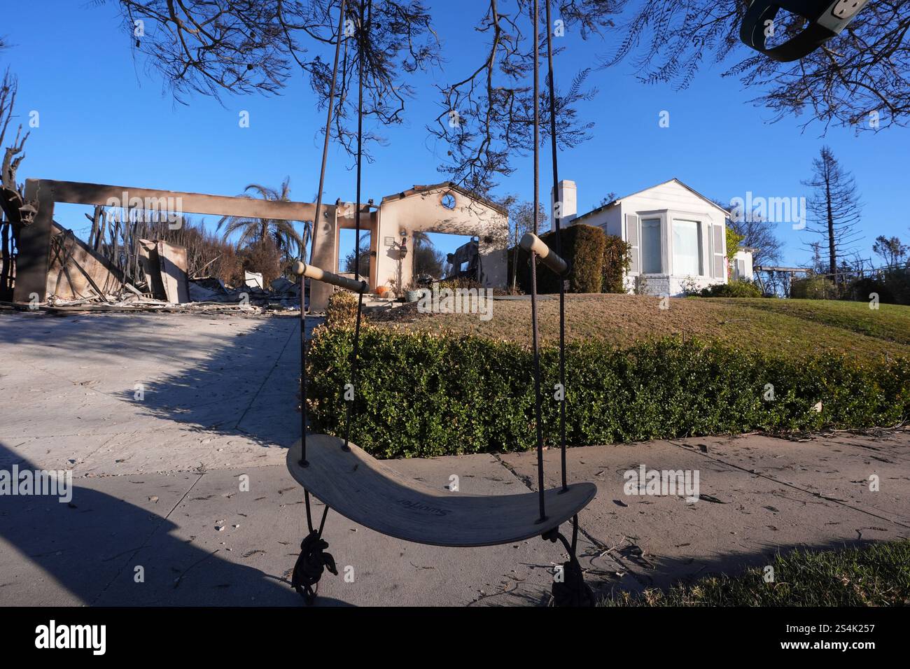 A swing hangs in front of an intact home and a home destroyed by the ...