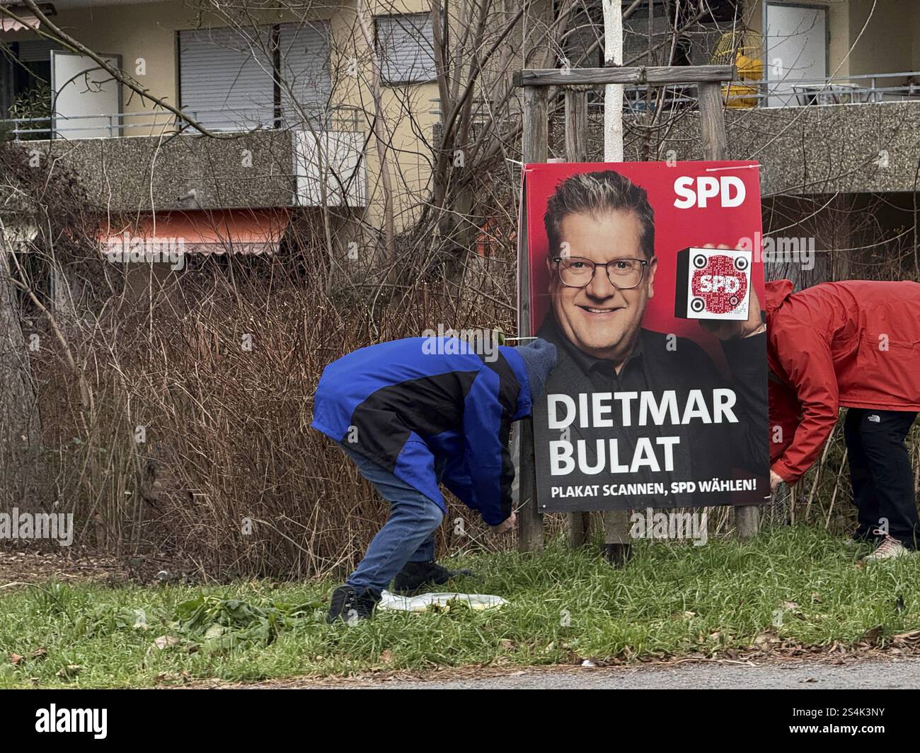 Two people, election workers, fix an SPD election poster on a green ...