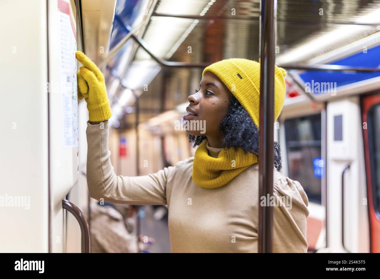 Tourist wearing yellow winter clothes checking subway map while ...