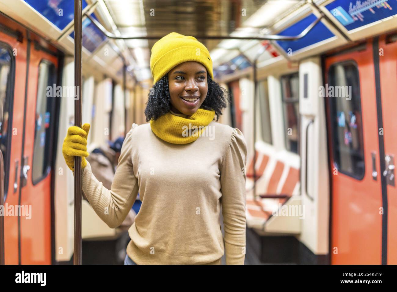 Young black woman wearing yellow wool cap and gloves standing inside ...