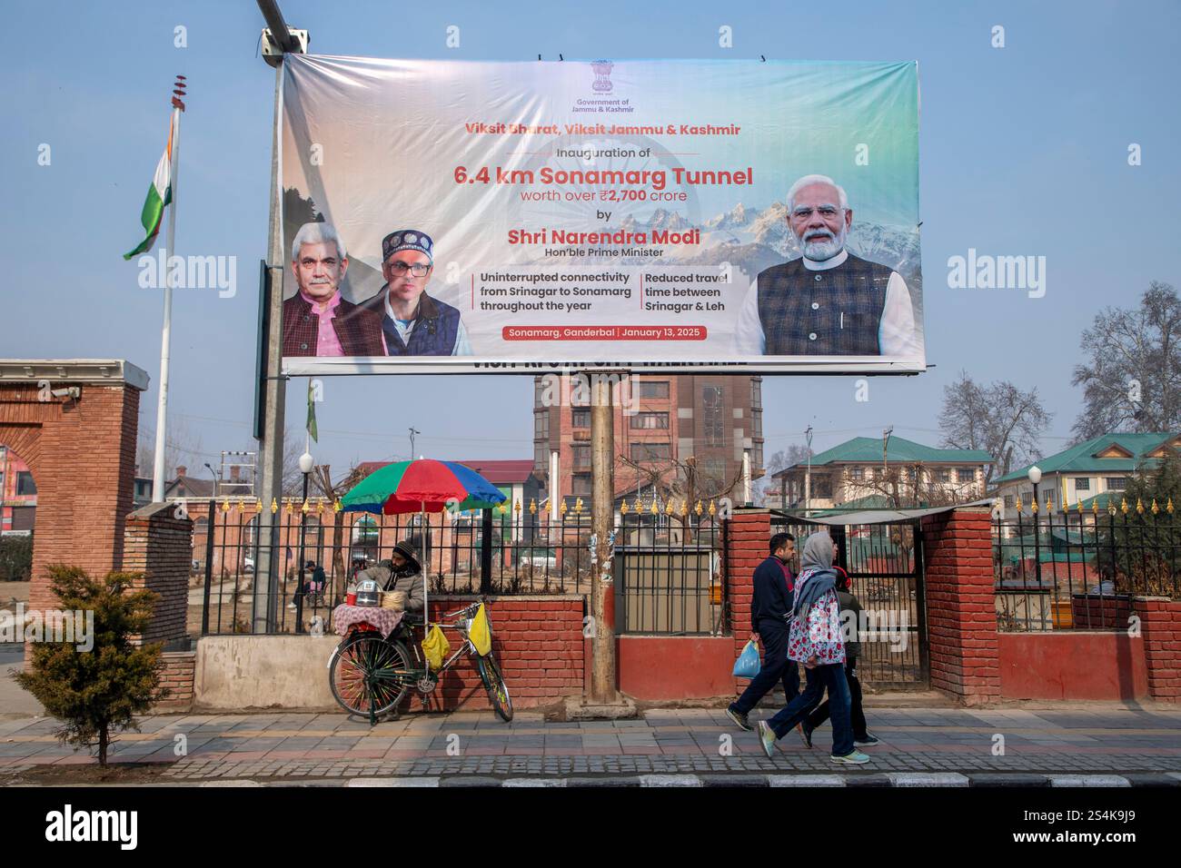 Kashmiri people walk past Narendra Modi's signage installed along a ...