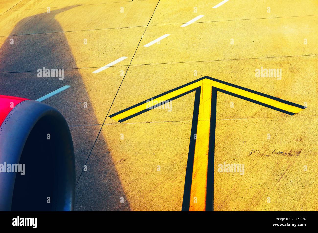 Yellow directional arrow on an airport runway, photographed from a ...