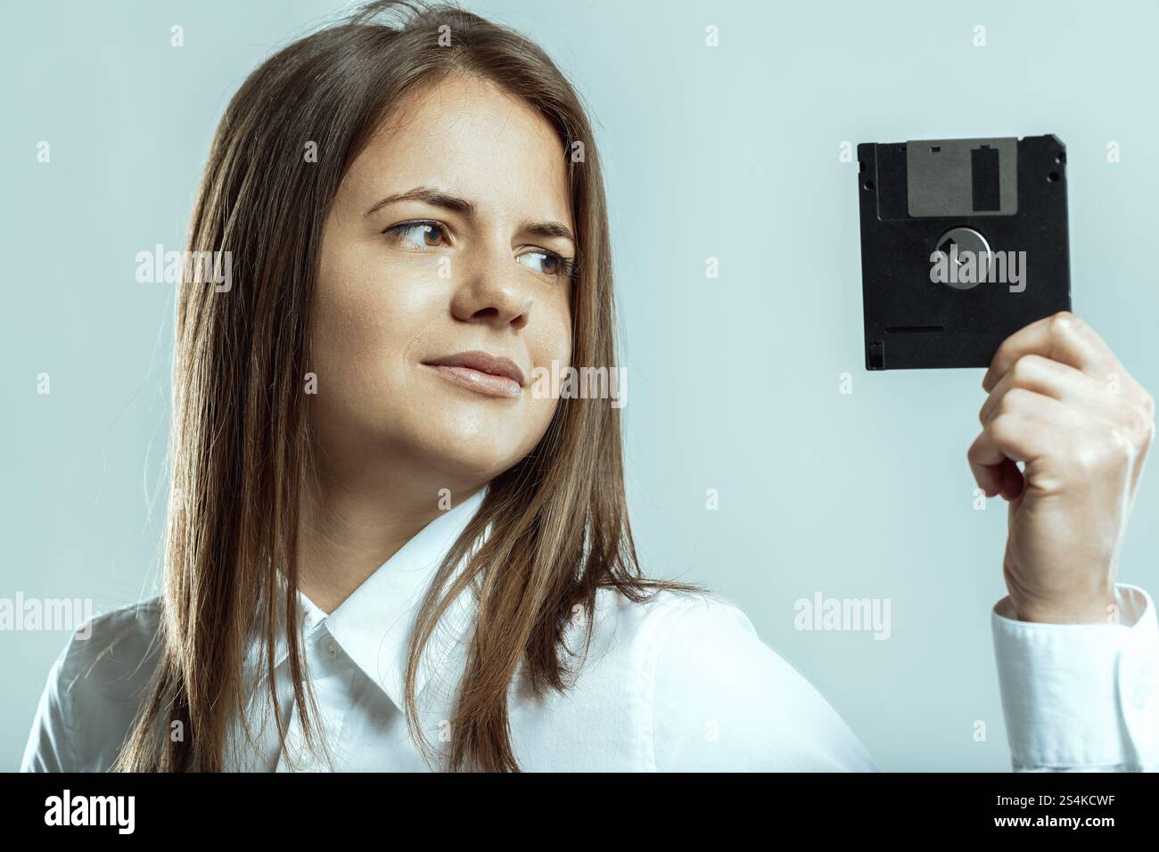 Young businesswoman holding a floppy disk looking up and smiling ...
