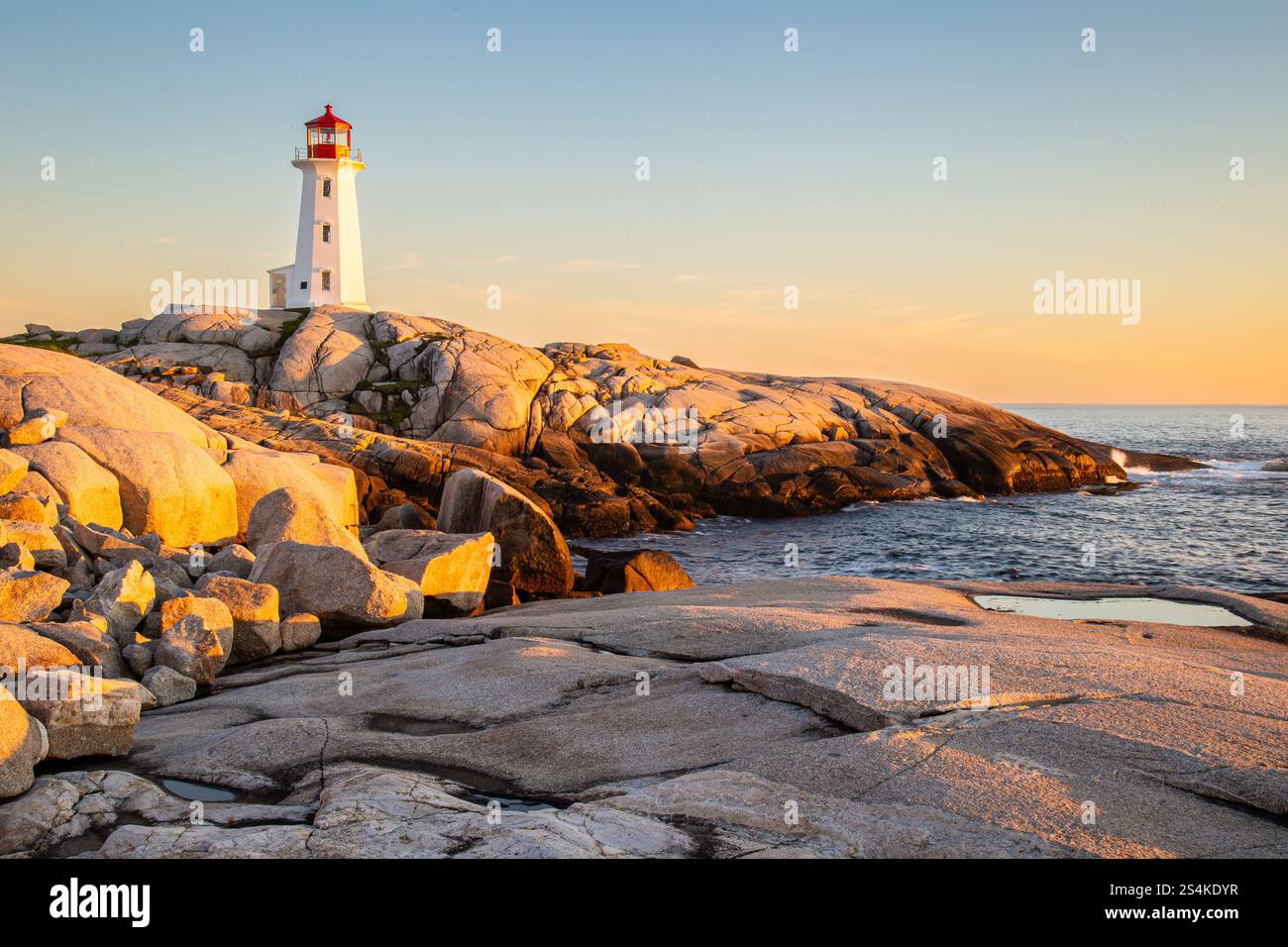Sunset by the coast at Peggy's Cove lighthouse in Nova Scotia. This ...