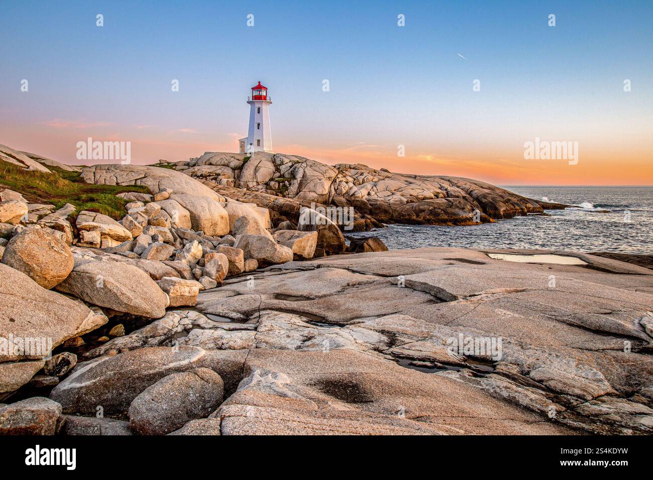 Sunset by the coast at Peggy's Cove lighthouse in Nova Scotia. This ...
