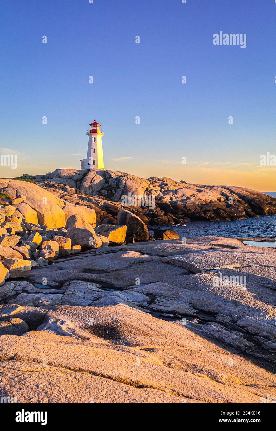 Sunset by the coast at Peggy's Cove lighthouse in Nova Scotia. This ...