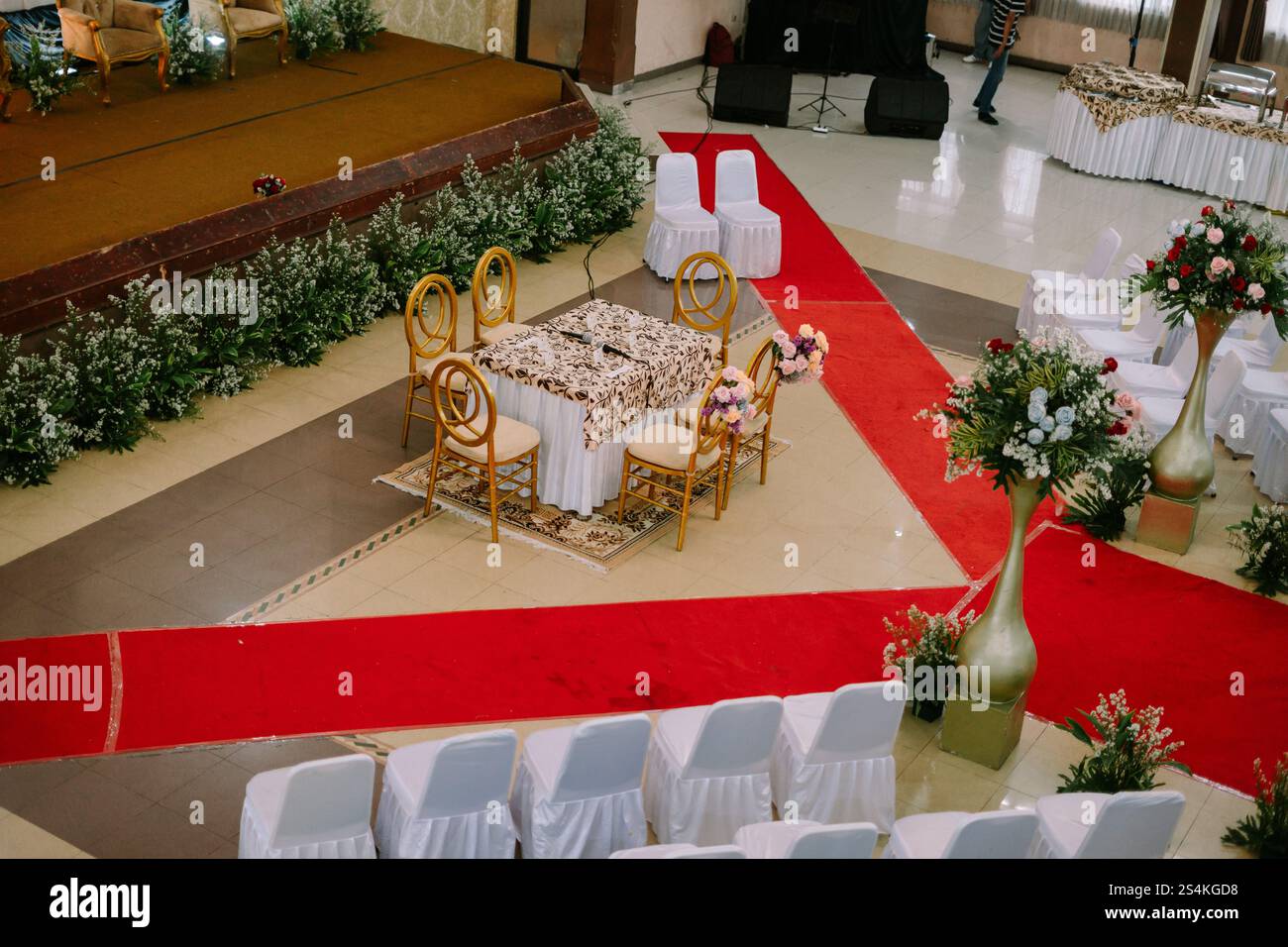 An elegant wedding reception setup with a red carpet, gold chairs ...