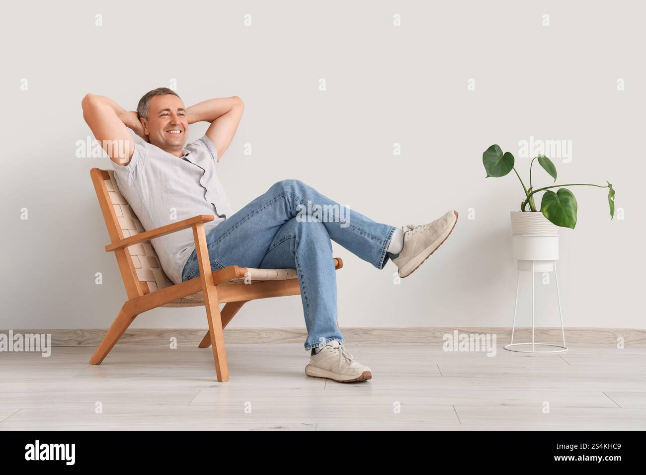 Old man resting in armchair near white wall Stock Photo - Alamy