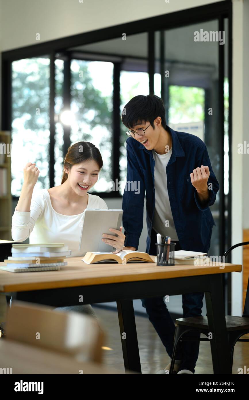 Excited two students celebrating their academic progress in study area Stock Photo - Alamy