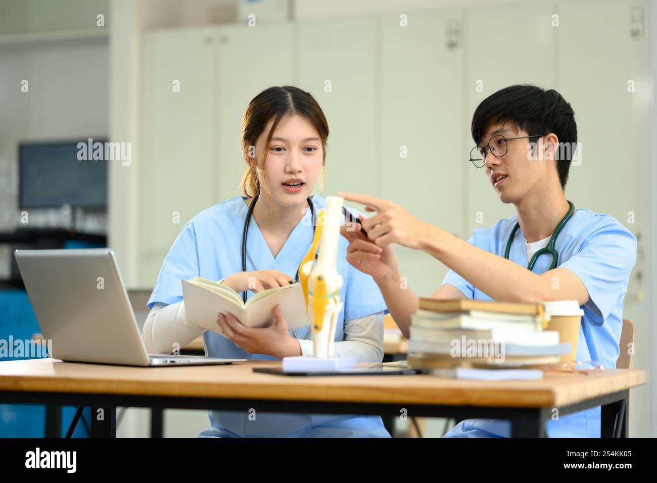 Two medical students discussing anatomy using skeletal model and taking ...