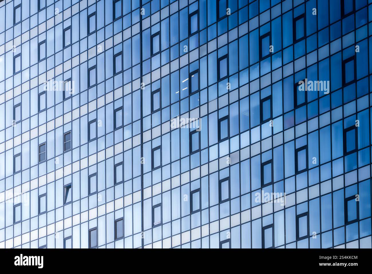 A single illuminated office window in a modern steel and glass bank ...