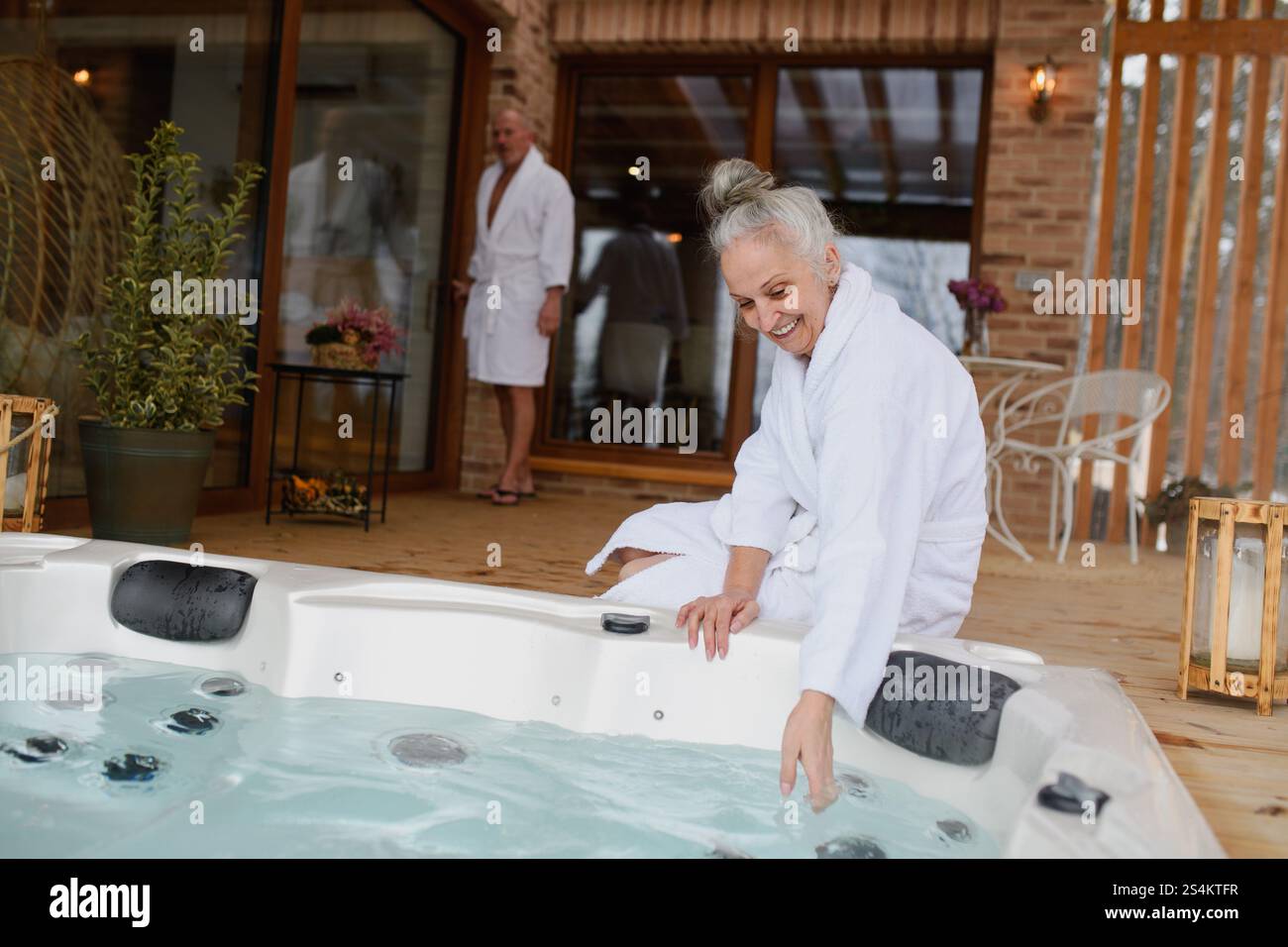 Older woman checking water temperature in hot tub with hand. Romantic ...