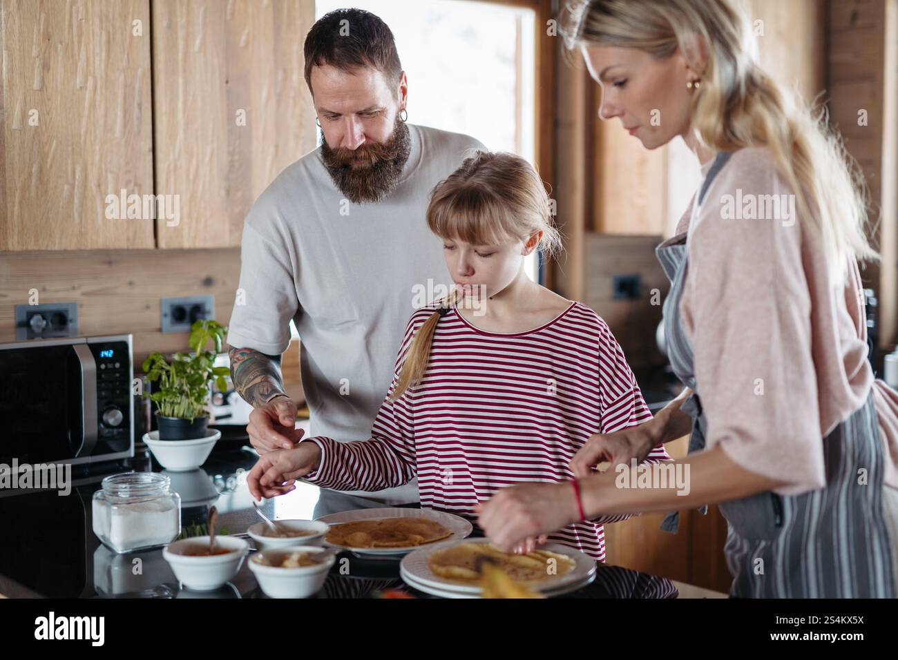 Family making pancakes, putting toppings on. Preparing sweet breakfast ...