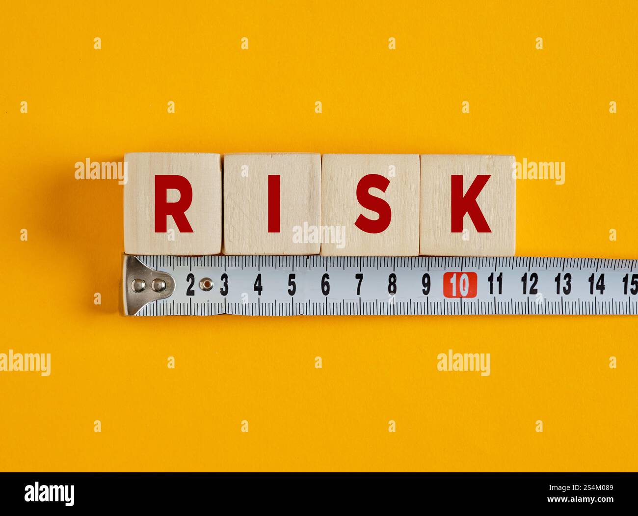 Wooden cubes with the word risk and a tape measure on a yellow ...