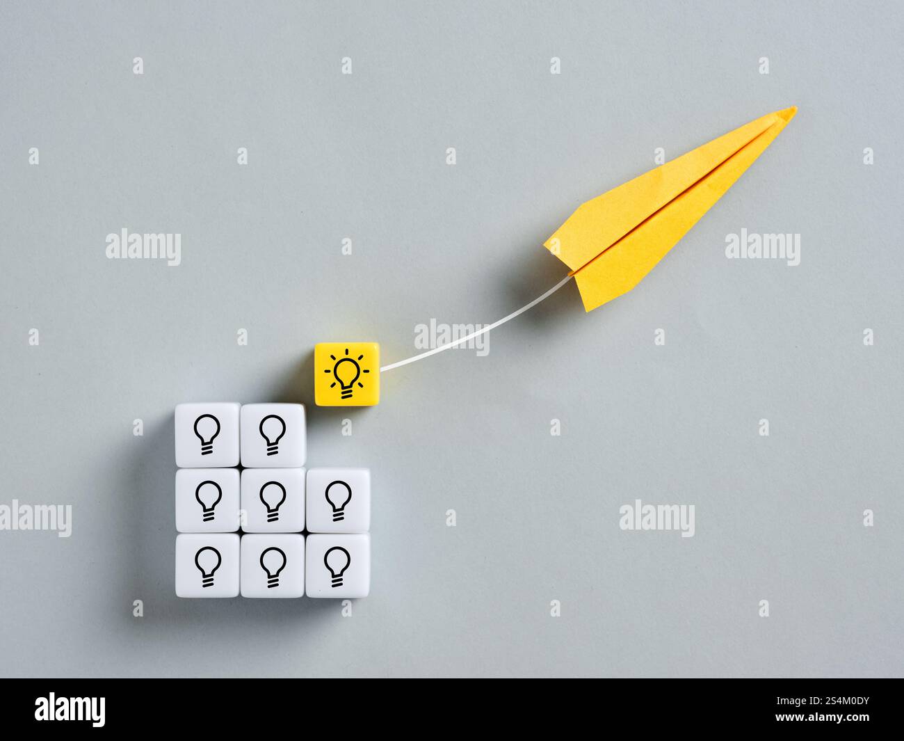 Paper airplane pulling a bright yellow light bulb from white cubes ...