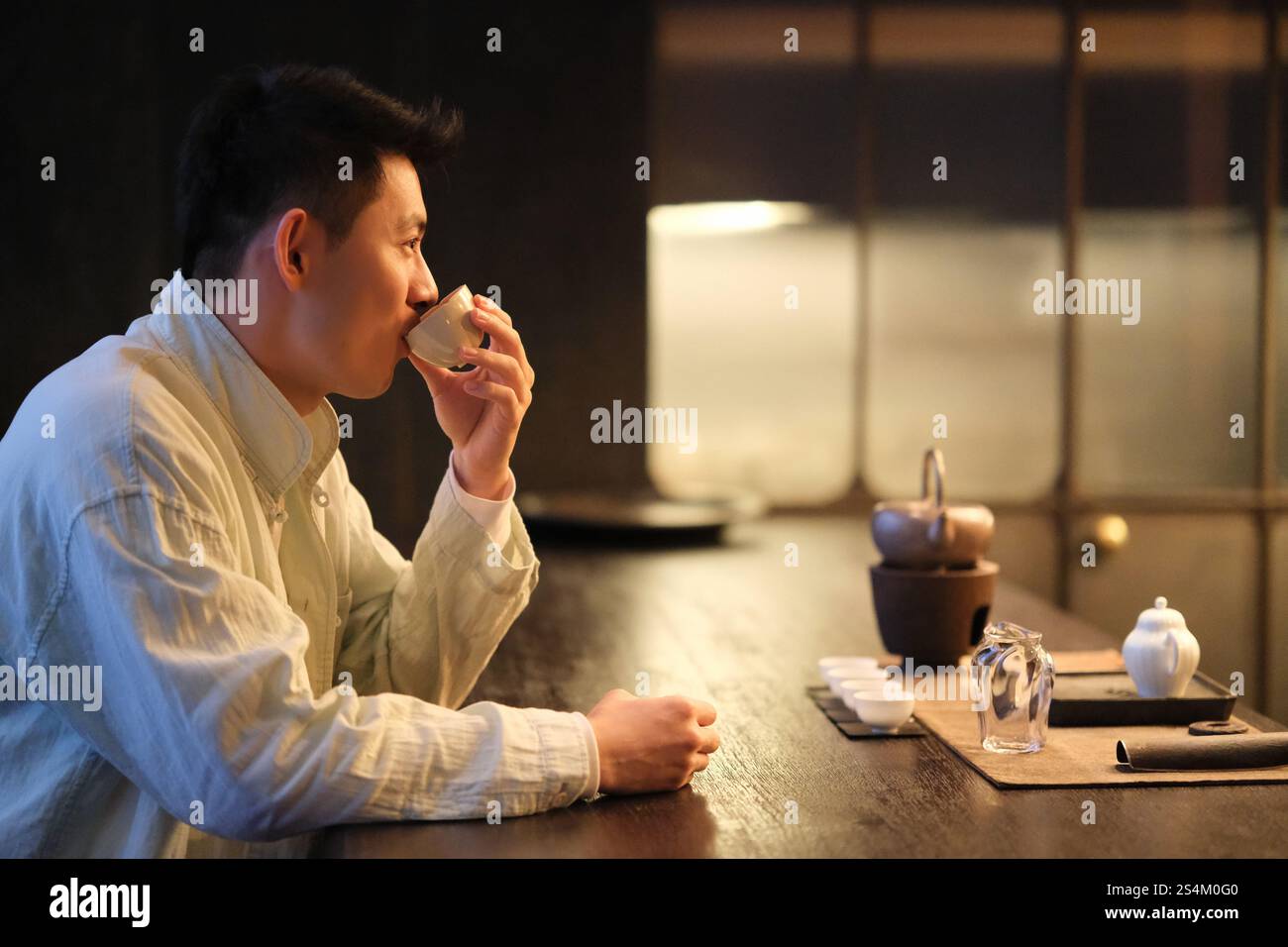 Chinese young man holding teacup drinking tea. Side view Stock Photo ...