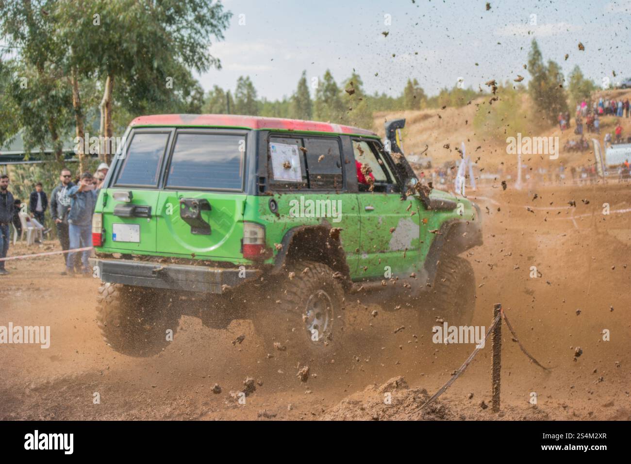 A green SUV is seen flying through the air, kicking up a cloud of dirt ...