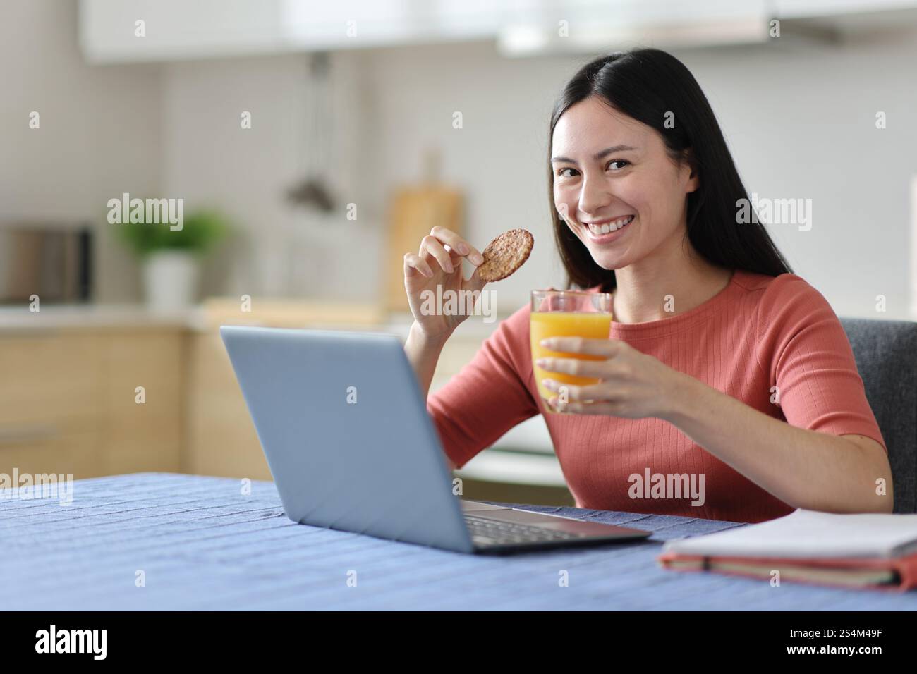 Happy asian student e-learning posing at breakfast with a laptop ...
