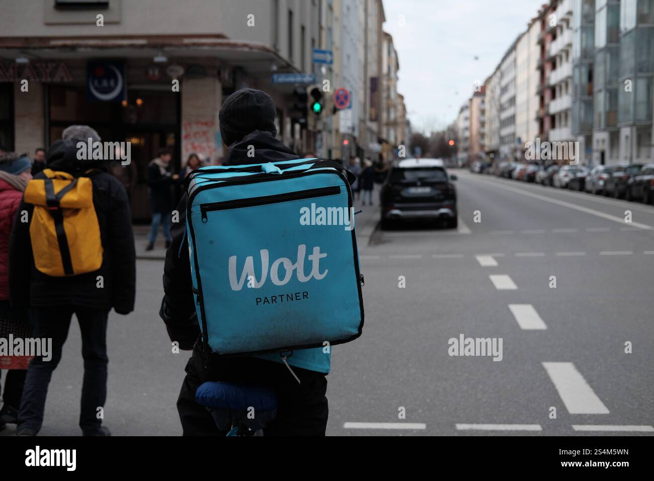 Wolt Fahrrardkurier an Ampel Wolt Fahrrardkurier an Ampel. Der Kurierfahrer kreuzt die Fußgänger ...