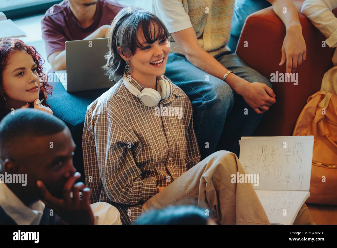 A group of engaged classmates sit informally, interacting and sharing ...